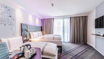 Quarto de hotel com uma cama, uma escrivaninha com uma bandeja de itens de café da manhã, uma televisão e uma parede com padrão de estrelas.