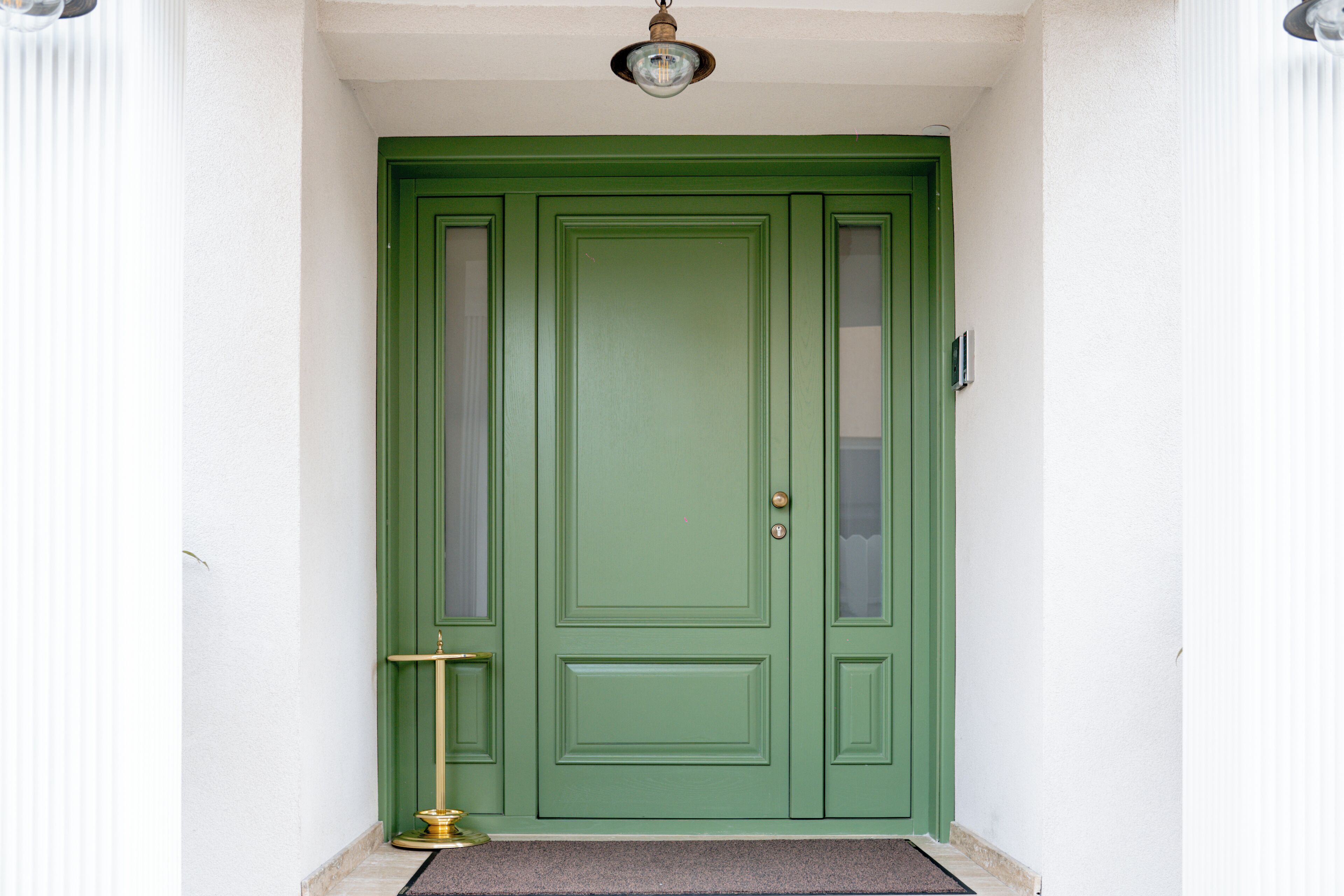 Uma porta verde com maçaneta e pequena alça de latão.