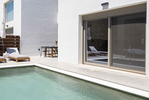 Uma área moderna de piscina ao ar livre com espreguiçadeiras e uma mesa.