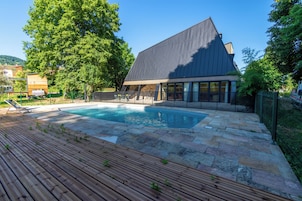 Um edifício moderno com piscina, rodeado por um deck de madeira e azulejos de pedra.