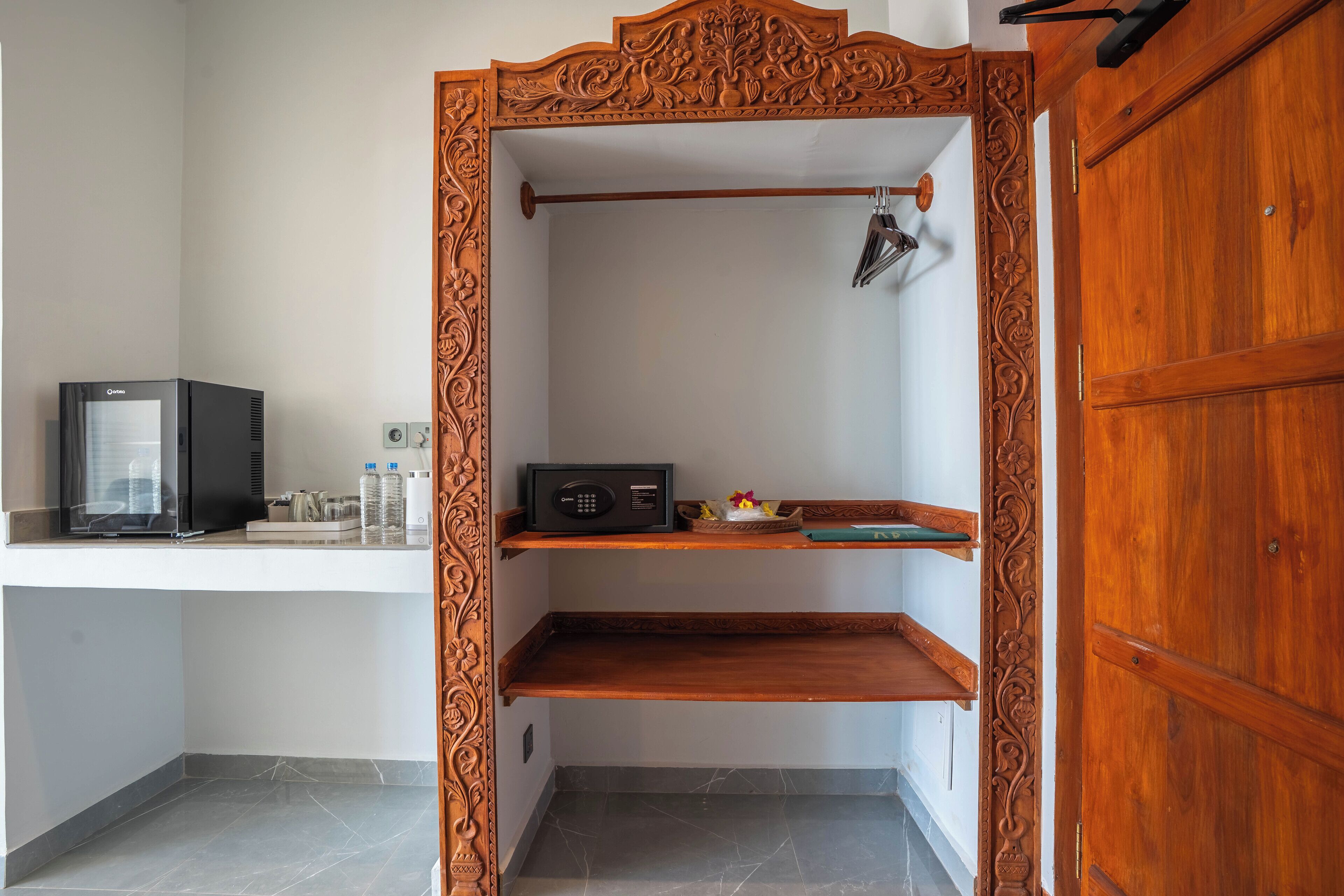 Quarto com armário de madeira, micro-ondas e prateleira com objeto decorativo.