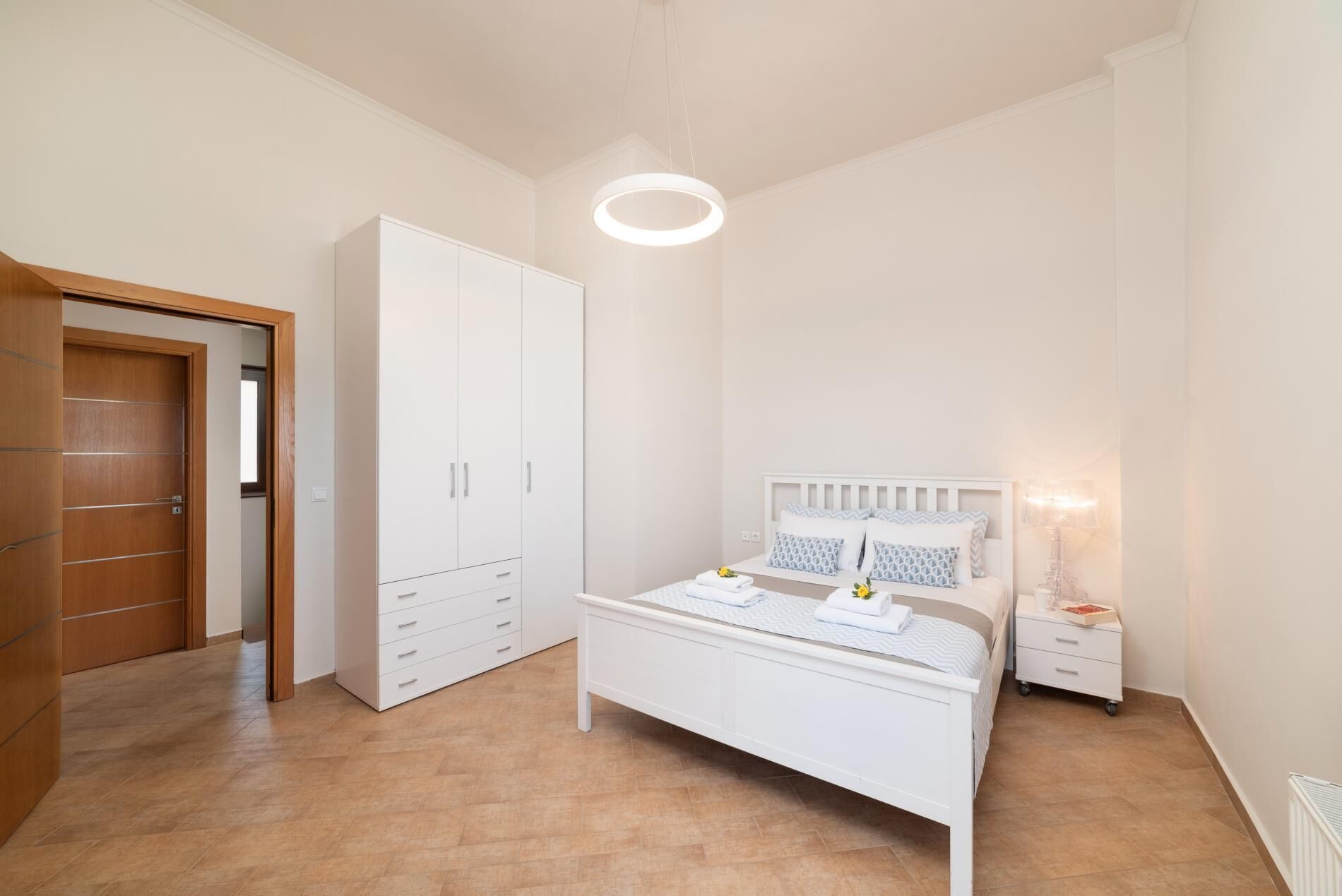 Um quarto com uma cama, um guarda-roupa, uma mesa de cabeceira e uma luminária.