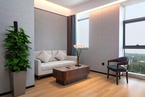 Uma sala de estar moderna com sofá, mesa de centro, poltrona, uma planta grande em vaso e um vaso com flores.