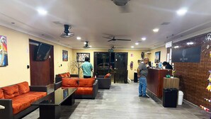 Um saguão de hotel com áreas de estar, um balcão de recepção e uma grande pintura na parede.