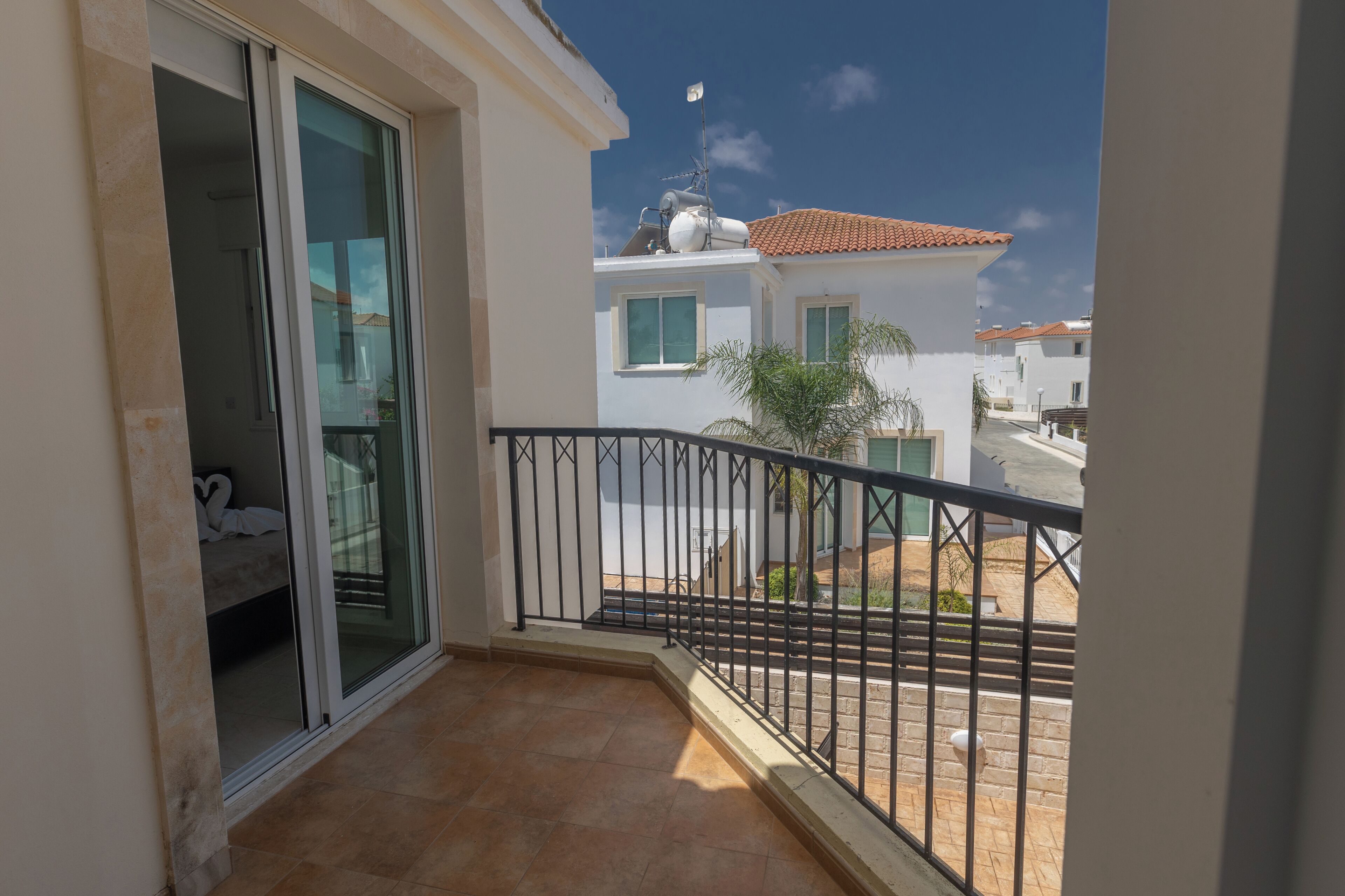 Varanda com porta de vidro que dá para um quarto, chão de azulejos e vista de edifícios vizinhos.