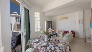 Uma área de refeições com uma mesa posta para quatro pessoas, um sofá e uma escada.