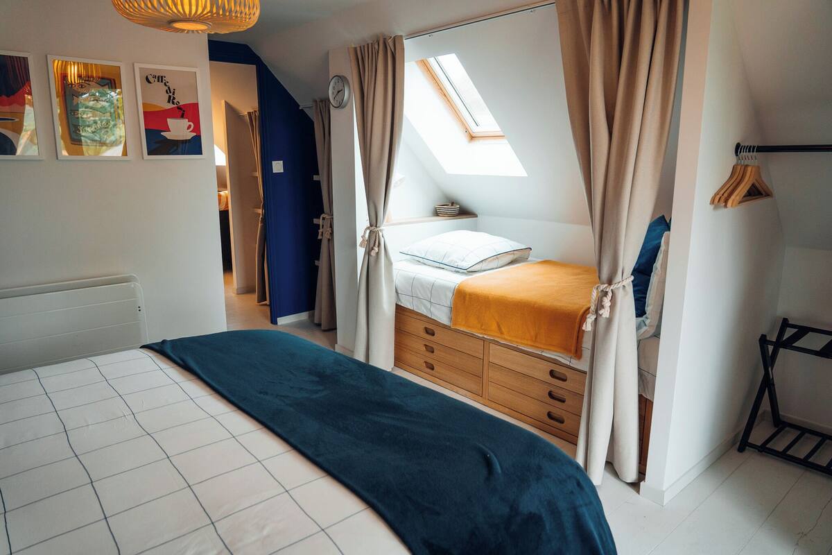 Quarto com cama, claraboia, guarda-roupa e cabideiro.