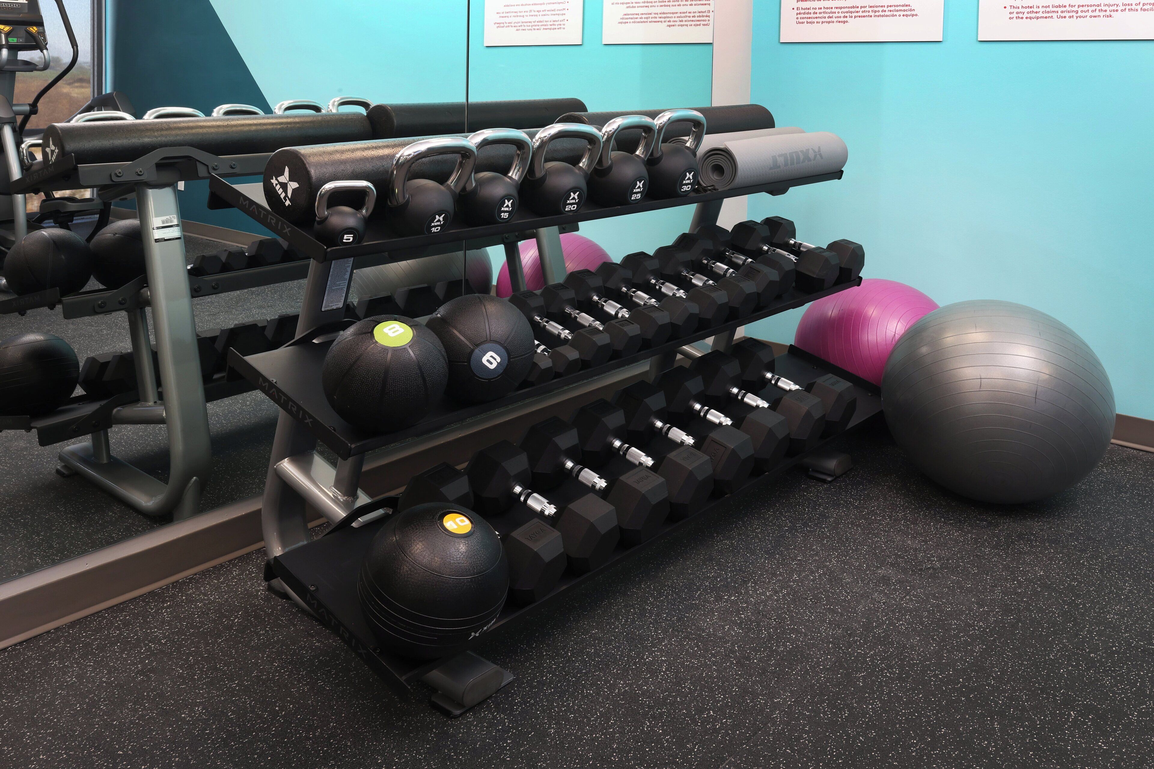 Academia com vários pesos e bolas de exercício.