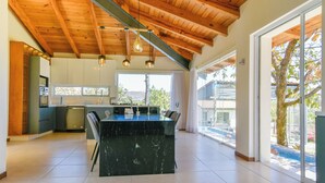 Uma cozinha moderna com uma ilha grande, vigas de madeira no teto e amplas janelas.