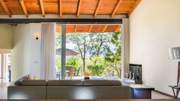 Uma sala de estar espaçosa com um sofá grande, uma televisão e vista para o exterior.