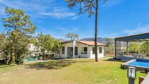 Uma casa moderna com piscina, varanda coberta e gramado bem cuidado.
