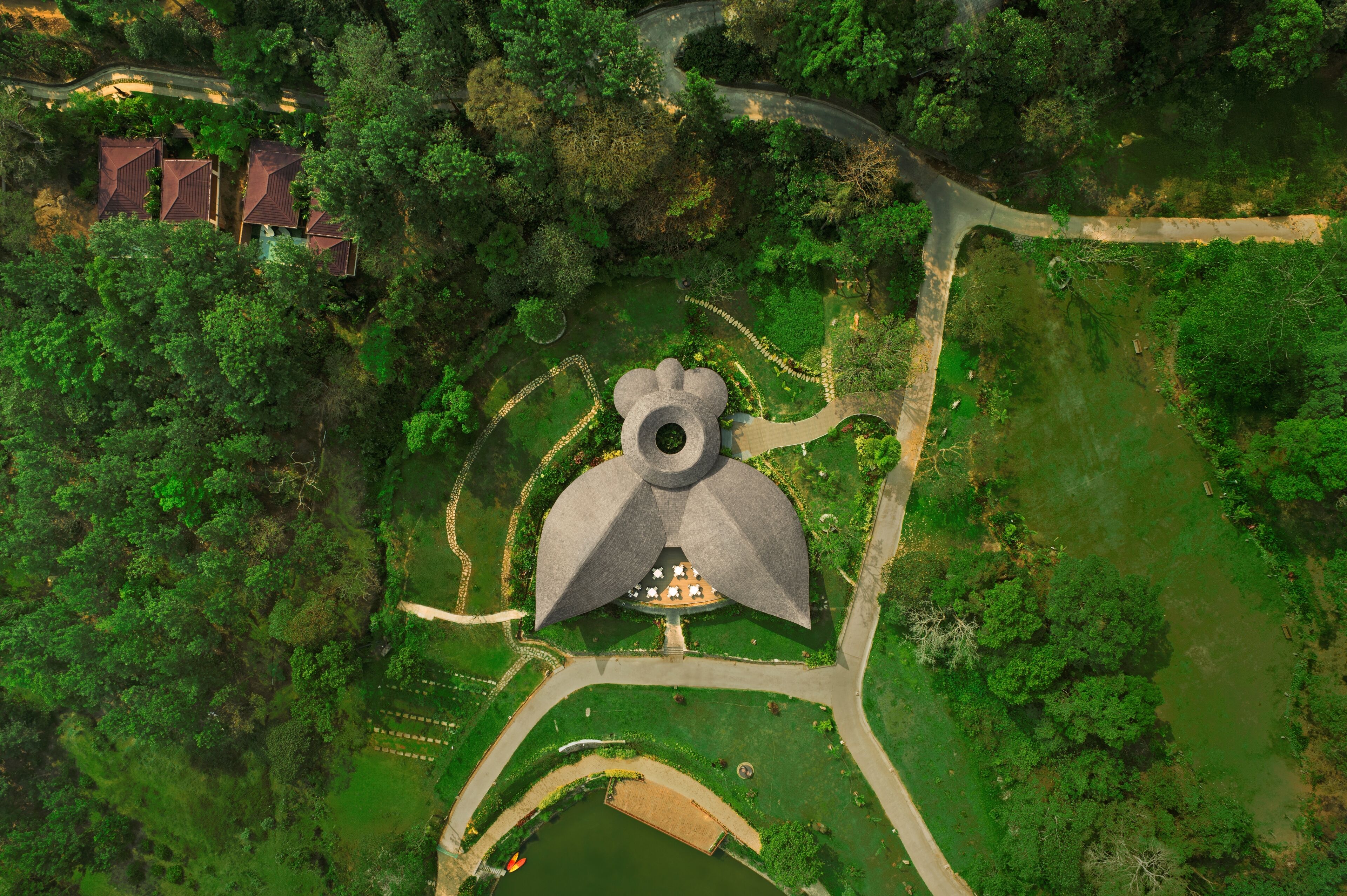 Vista aérea de um parque com uma estrutura em forma de cúpula, rodeada por vegetação e caminhos.
