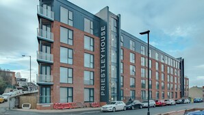 Um edifício moderno de vários andares com uma placa de destaque que diz "Priestley House".