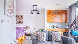 Um apartamento moderno com um sofá cinzento, uma mesa de jantar de madeira e uma cozinha com armários de madeira.
