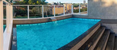 Piscina no terraço com vista ampla da paisagem urbana ao fundo.