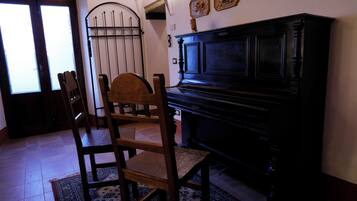 Um quarto com um piano, uma cadeira, um tapete e uma porta.