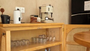A kitchen counter with a coffee maker, a kettle, and a coffee waste bin.