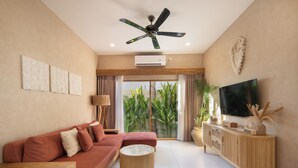 A modern living room with a sofa, a coffee table, a TV, and a ceiling fan.