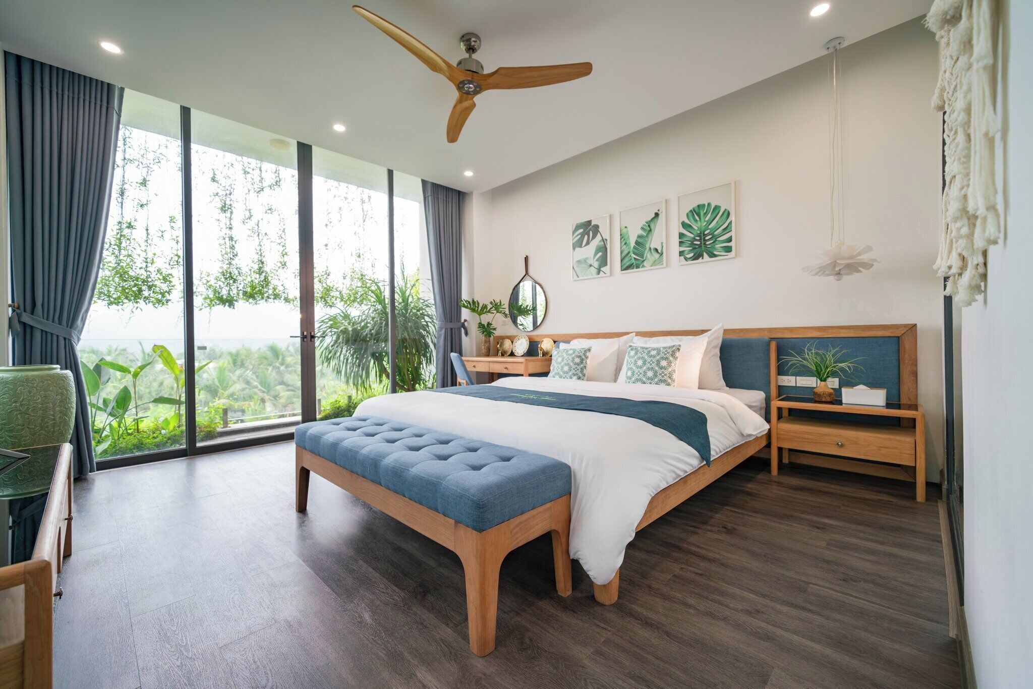 Quarto moderno com cama grande, banco de madeira e ventilador de teto.