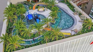 Uma área de piscina no terraço com um escorregador azul, palmeiras e cadeiras de descanso.