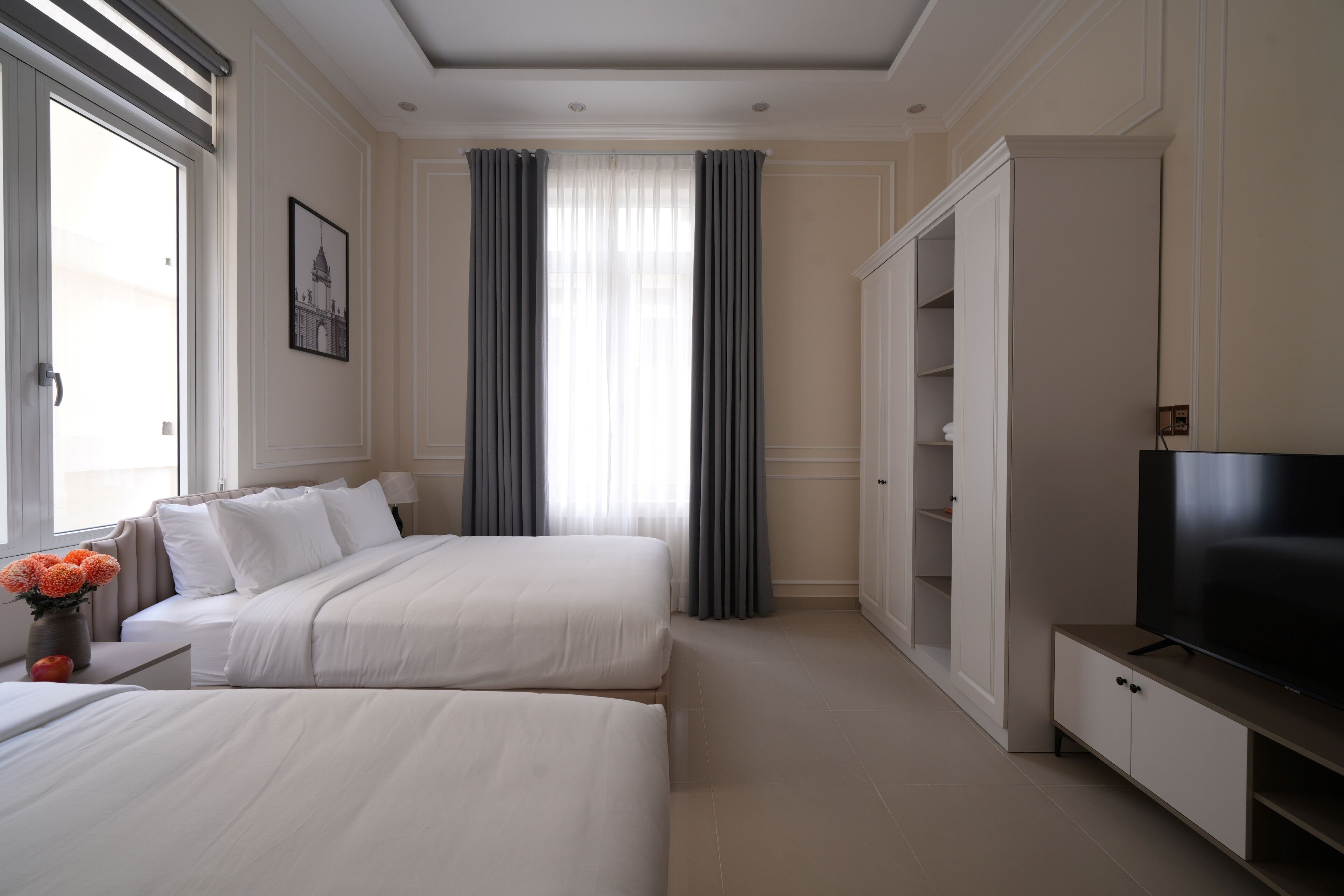 Quarto de hotel com duas camas, uma televisão e um guarda-roupa.