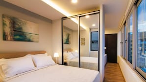 Quarto de hotel com cama grande, armário de portas deslizantes e vista para a cidade.