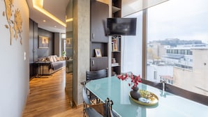 Uma sala de estar moderna com uma mesa de jantar de vidro, um sofá e uma TV fixada na parede.