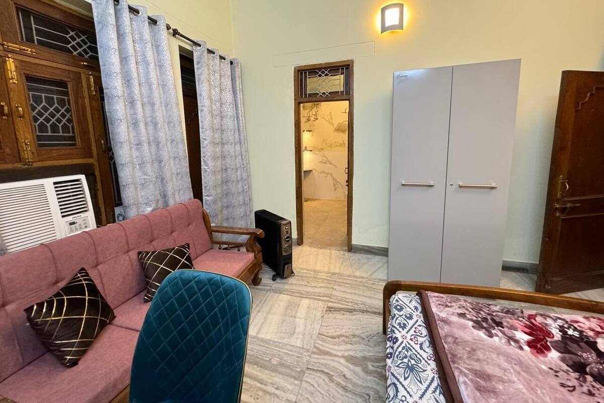 Uma sala de estar com sofá, poltrona, mesa, guarda-roupa e radiador.