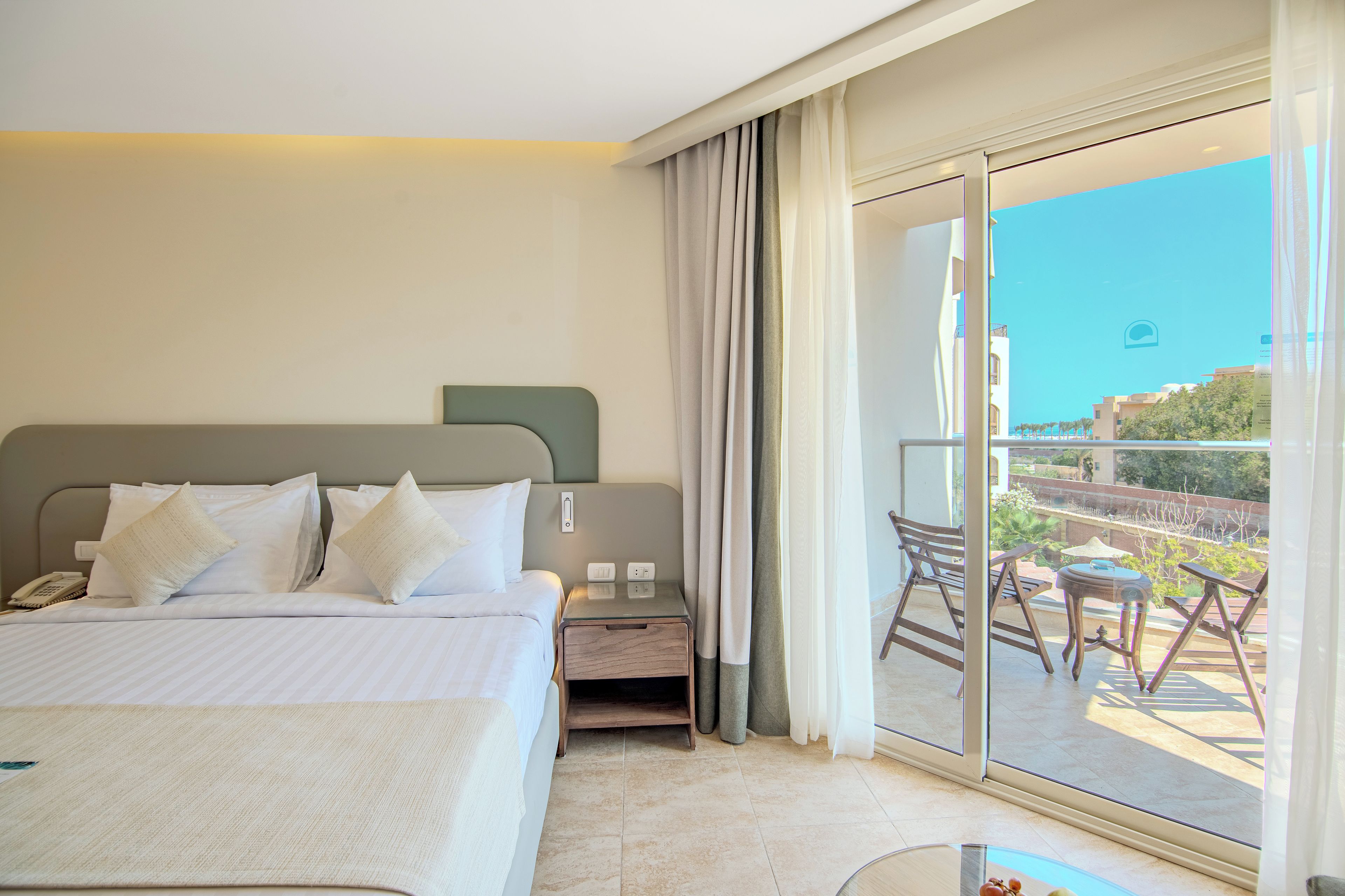 Quarto de hotel com cama, mesa de cabeceira e vista para o exterior.