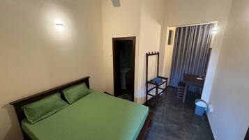 Quarto com cama, ventilador de teto, banheiro pequeno e vista para o exterior.