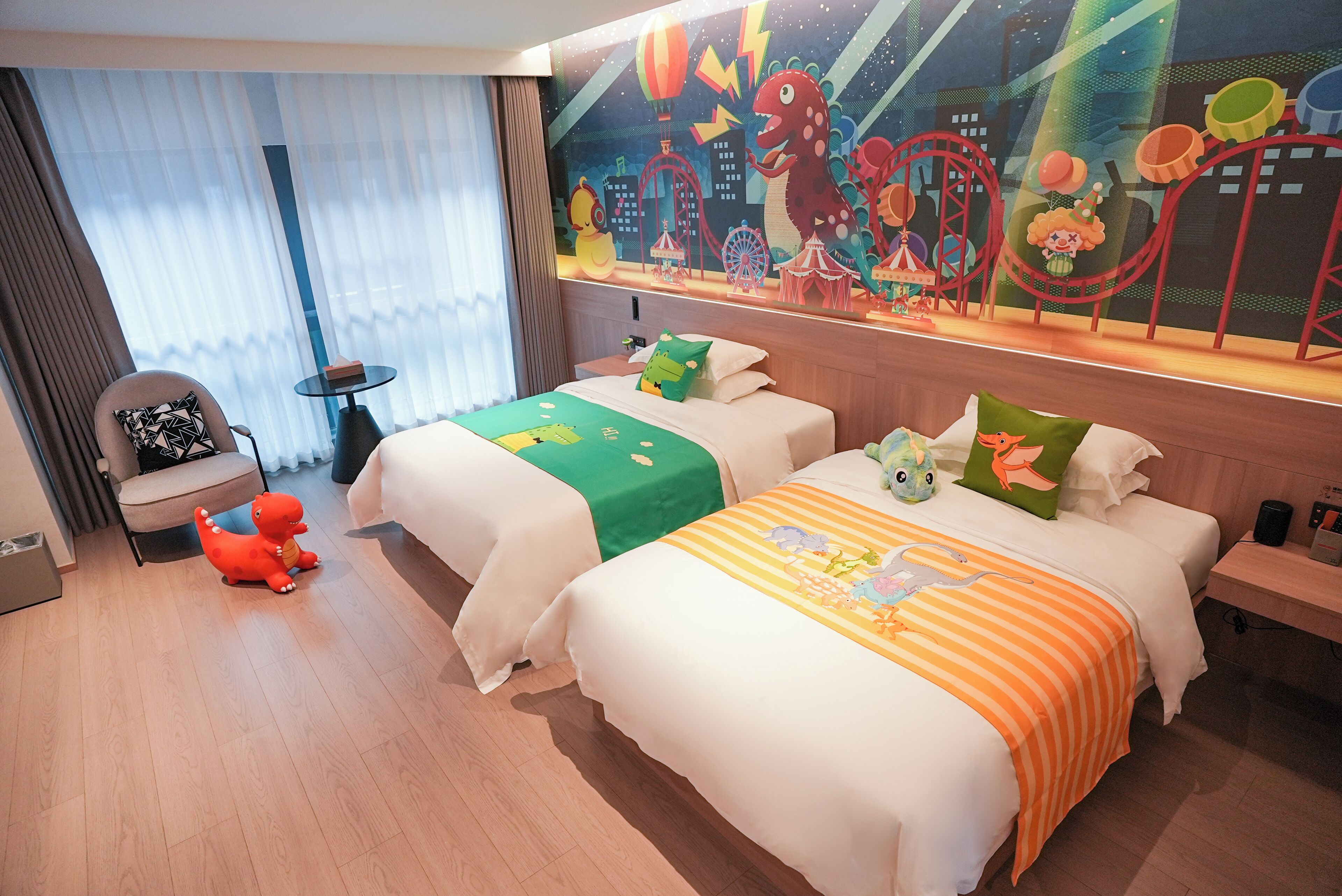 Quarto de hotel com duas camas, uma cadeira, uma mesinha e um mural colorido na parede.