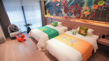 Quarto de hotel com duas camas, uma cadeira, uma mesinha e um mural colorido na parede.