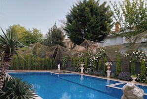Piscina com superfície de água azul cristalina, rodeada por vegetação exuberante e plantas decorativas.