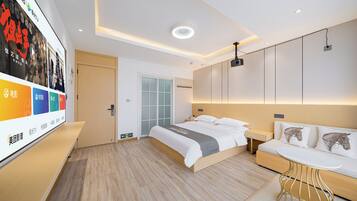 Quarto de hotel moderno com cama, sofá, televisão e escrivaninha.