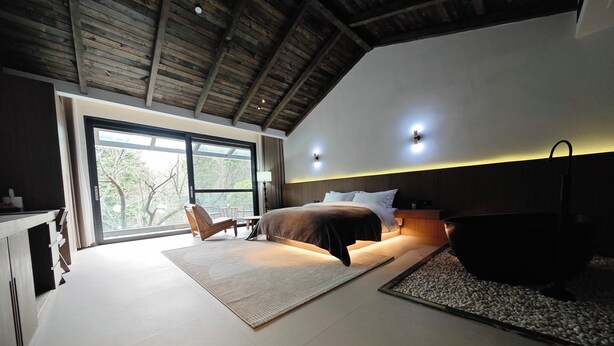 Quarto moderno com uma cama grande, um espaço para sentar e uma banheira.