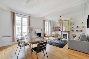 Uma sala de estar ampla com área de jantar, lareira e um espelho grande.