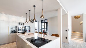 Cozinha moderna com ilha central, iluminação pendente e piso estampado.
