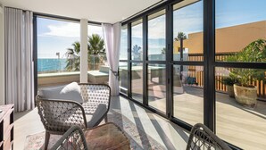 Uma varanda com cadeiras de vime, uma mesa e vista para o mar.