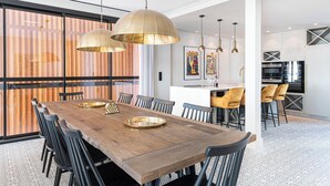 Uma sala de jantar moderna com mesa de madeira, cadeiras pretas e iluminação pendente.