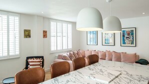 Uma área de jantar moderna com mesa de mármore, cadeiras de couro marrom e uma luminária pendente grande.