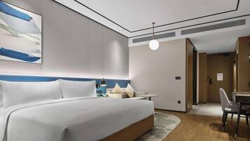 Quarto de hotel moderno com uma cama grande, mesas de cabeceira, uma escrivaninha e uma cadeira.