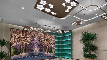 Um lobby moderno com parede estampada, iluminação embutida e uma parede curva com detalhes em verde-água.