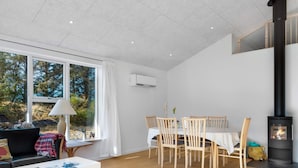 Uma sala de estar moderna com área de jantar, lareira e grandes janelas.
