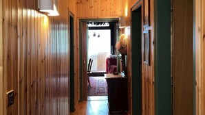 Um corredor de madeira com tapete estampado, paredes de madeira e uma porta que dá para um quarto.
