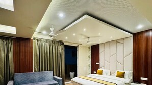 Quarto moderno com cama, sofá, mesinha e ventoinha no teto.