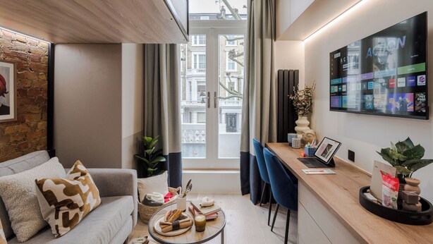 Uma sala de estar moderna com sofá, mesa de centro e escrivaninha com laptop.