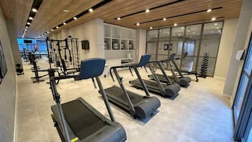 Uma academia com esteiras, aparelhos de musculação e bolas de exercício.