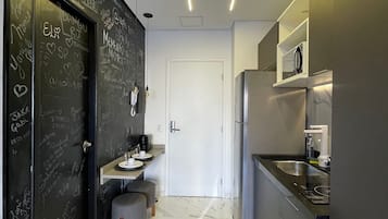 Uma cozinha moderna com piso de mármore, um quadro negro com anotações e uma geladeira de aço inoxidável.