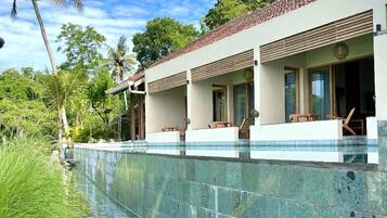Um resort moderno com piscina, deck de madeira e vegetação tropical.
