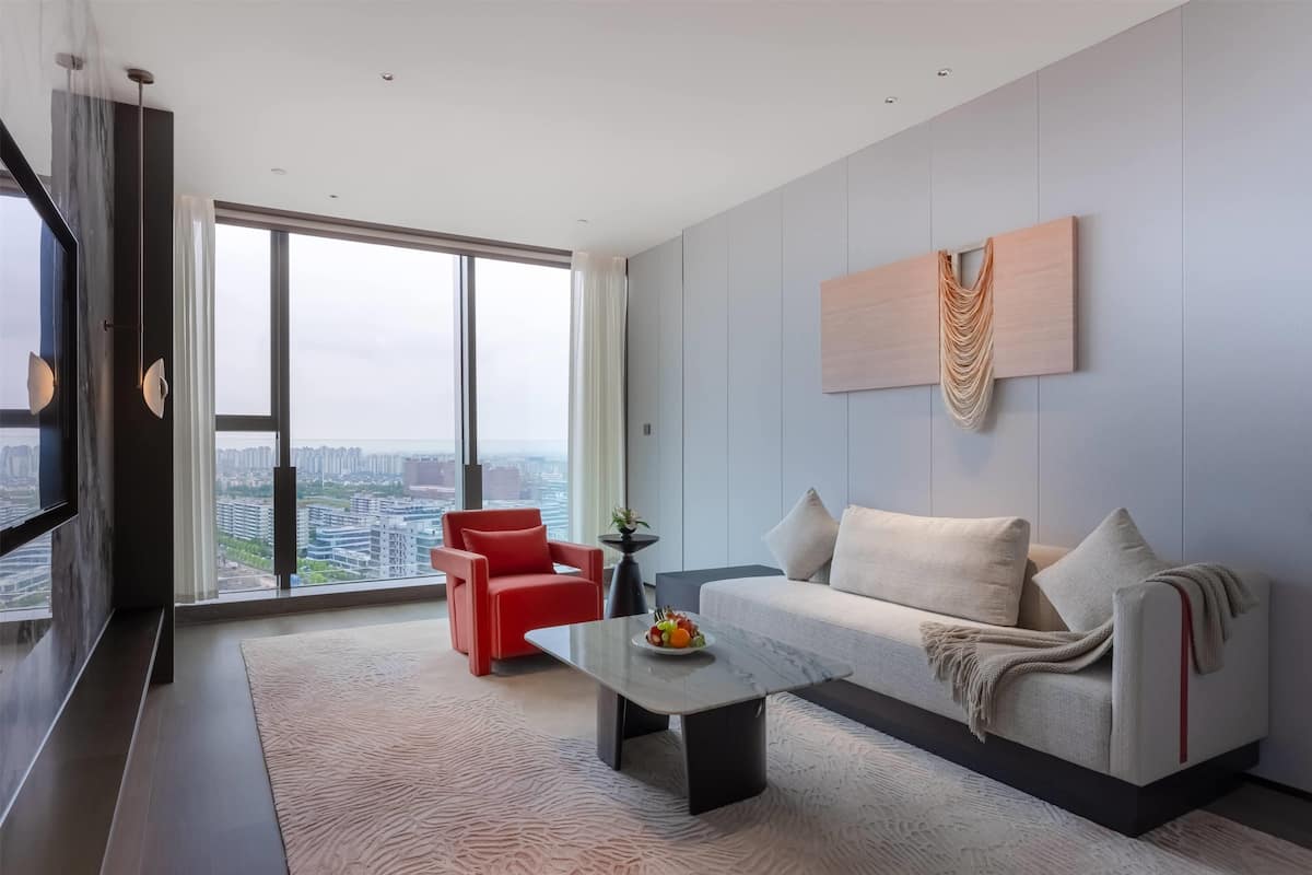 Uma sala de estar moderna com sofá, poltrona vermelha e mesa de centro com frutas.